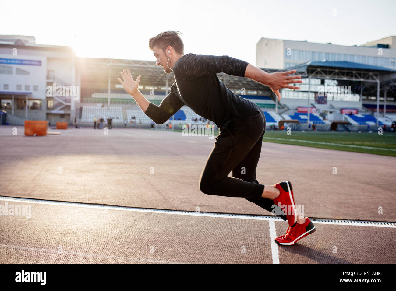 athlete in black clothes starting sprint on running track Stock Photo ...