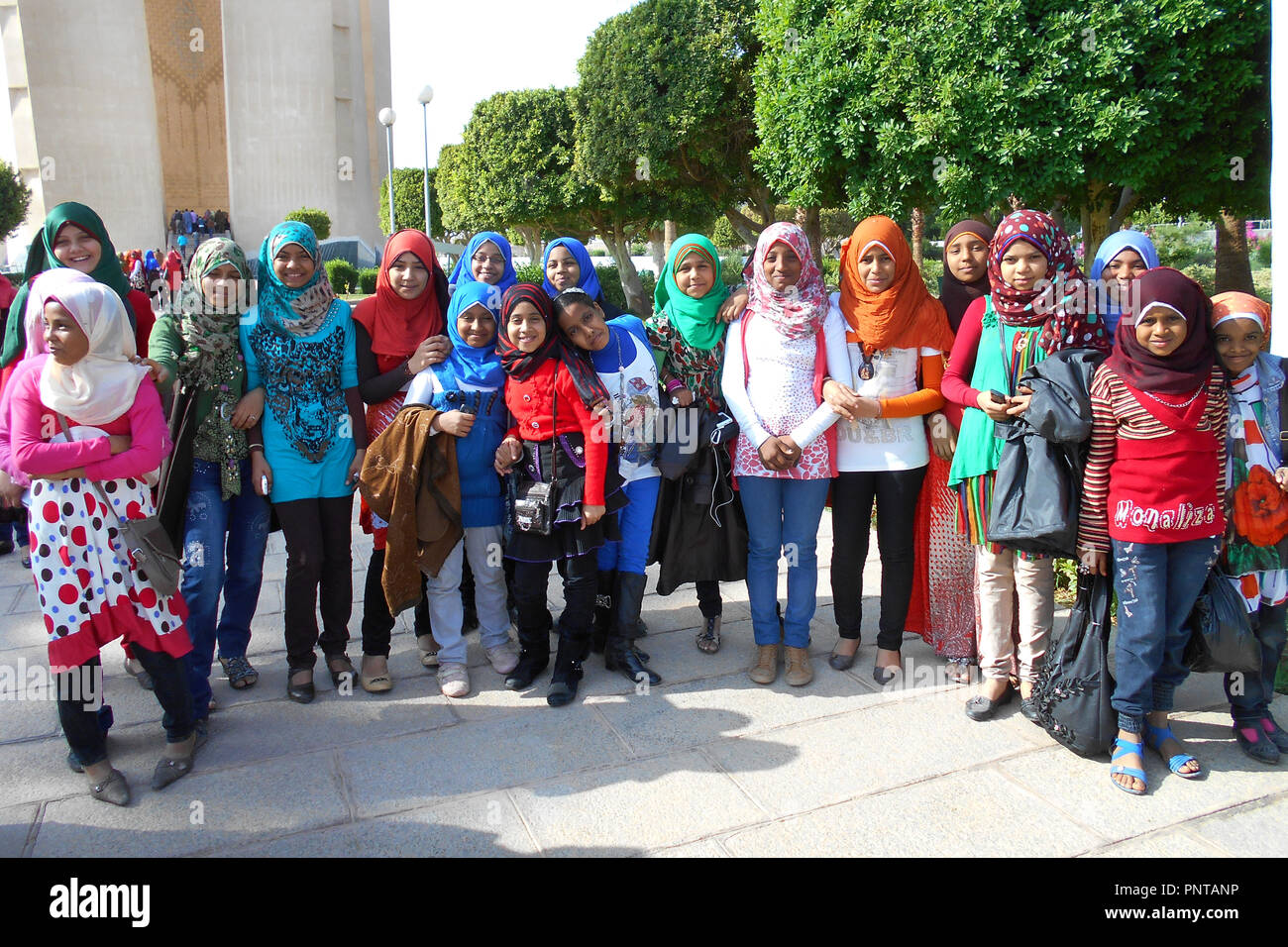 A large group of colourfully clothed Egyptian school girls smiling and ...