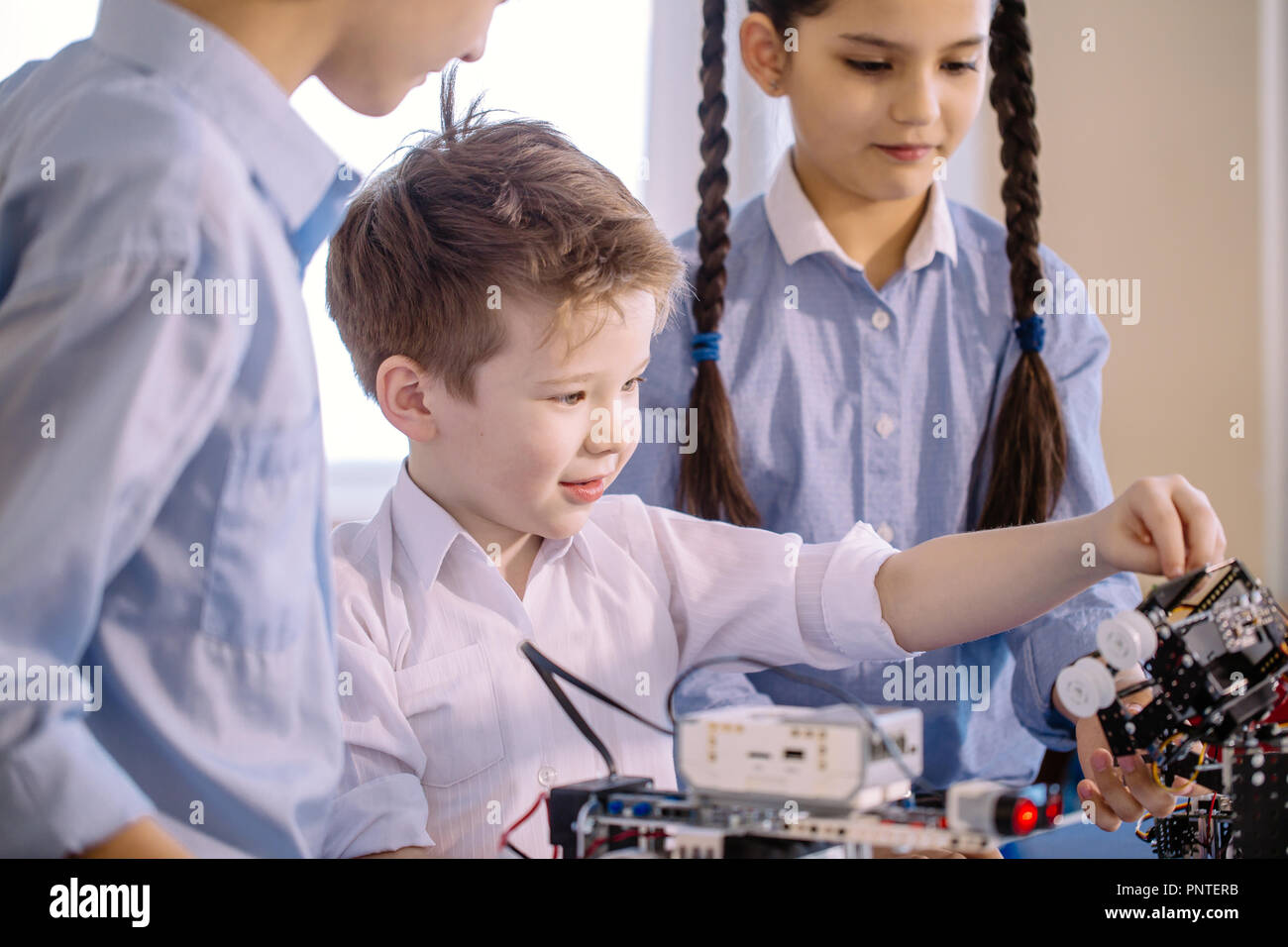 Kids playing with electrical robot while visiting robotics exhibition ...