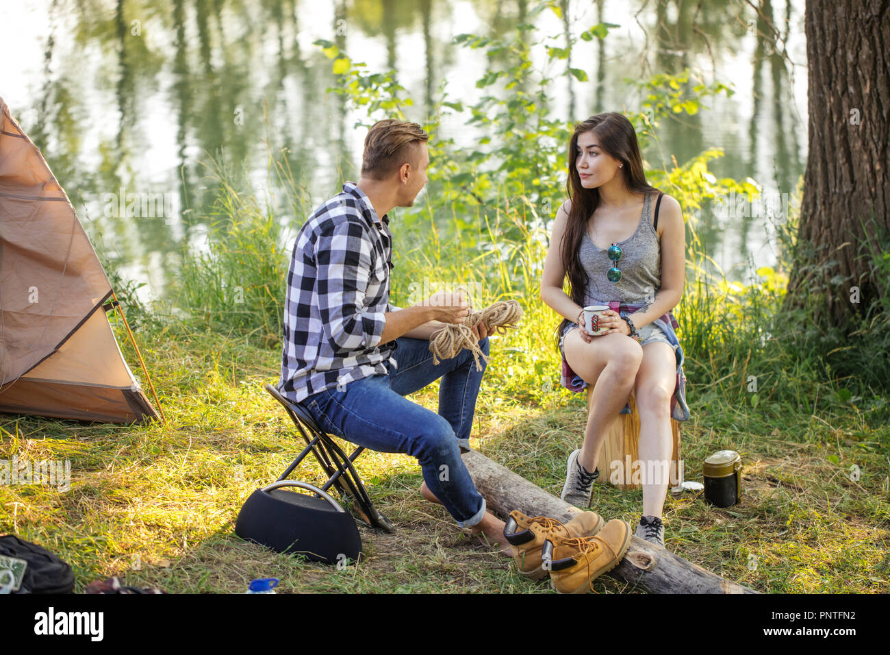 brunette girl is listening to her boyfriend while sitting on the stump ...