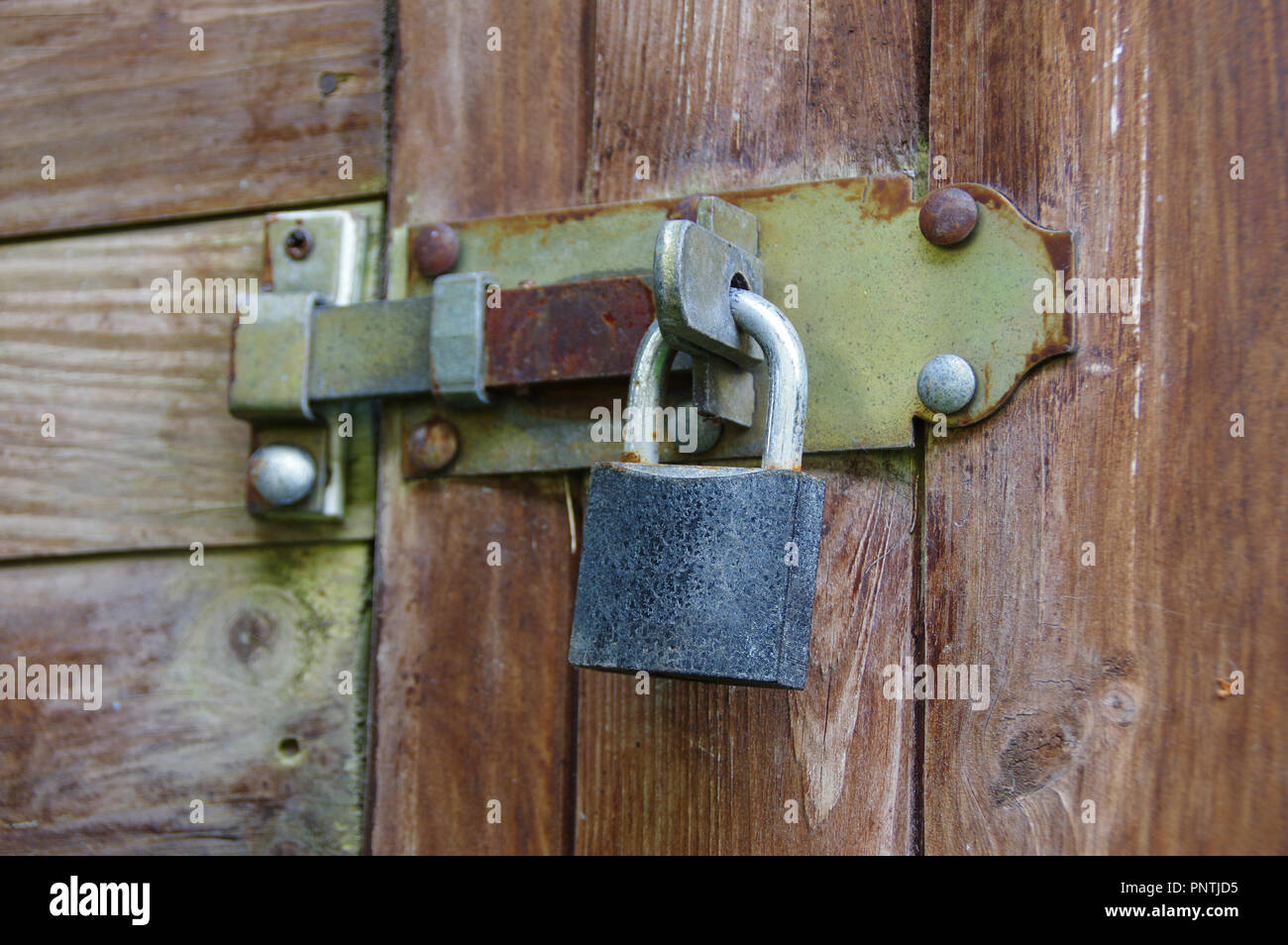 Rusted old padlock on latch. Vintage lock protecting a wooden door ...
