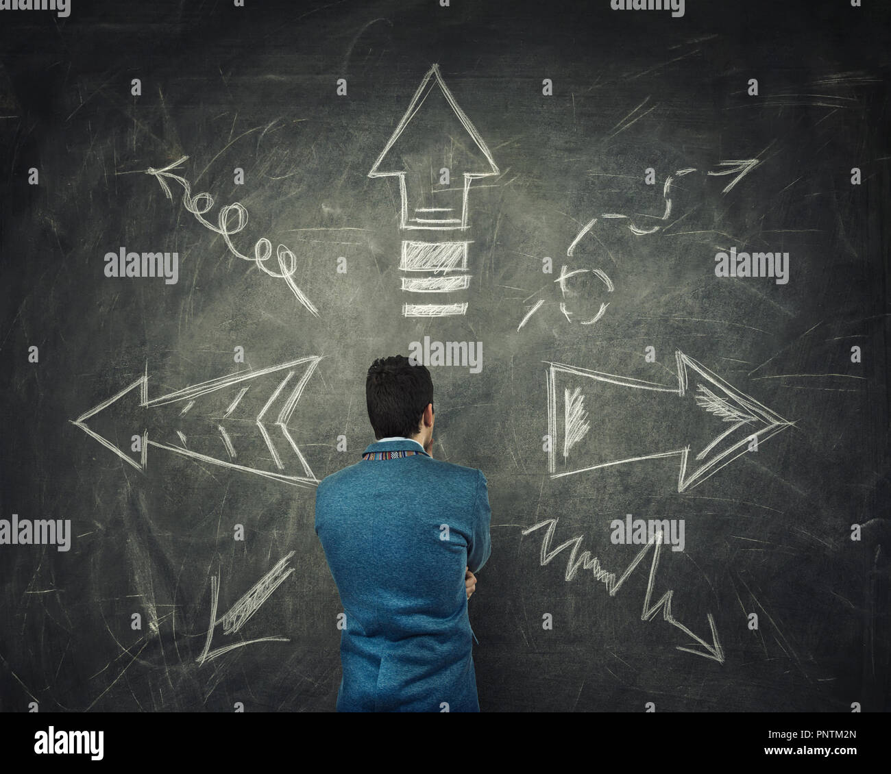 Rear view of pensive businessman thinking in front of a huge blackboard ...