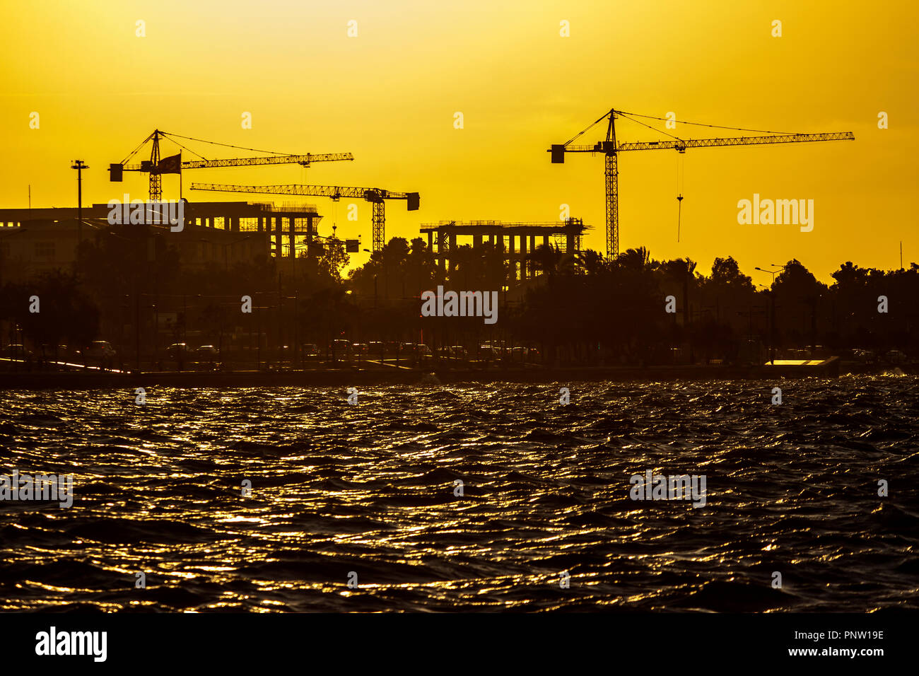 Cranes of a construction workshop at Izmir (Turkey) during sunset Stock ...
