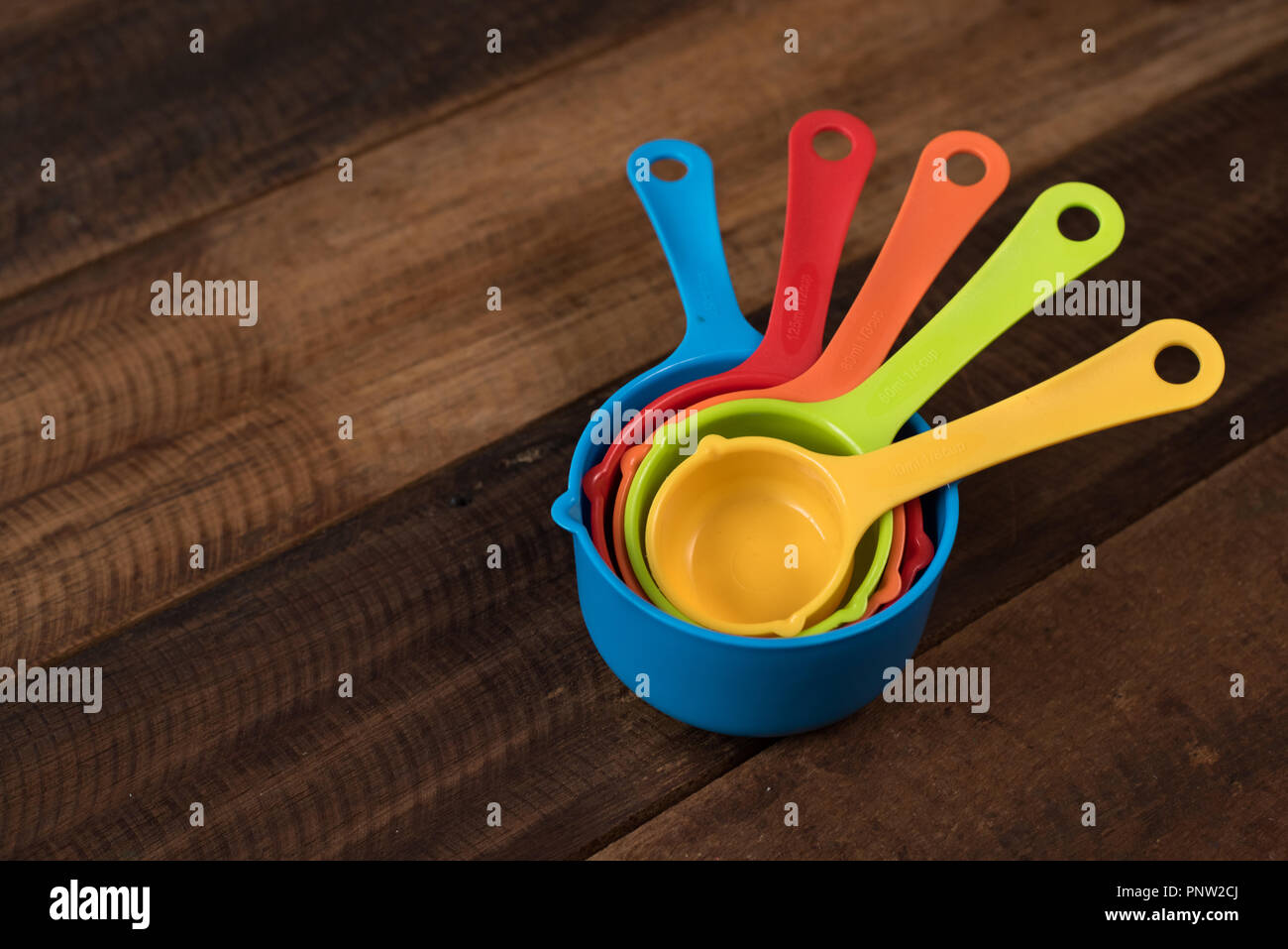 colorful measuring cups on a wooden table. Kitchen utensils concept ...