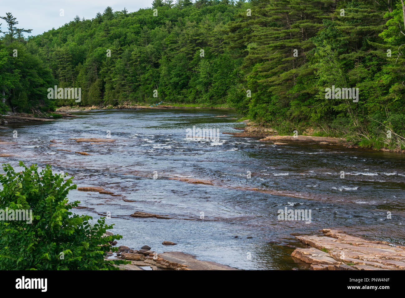 The Ausable River in the summer time flowing over rocks to form rapids ...