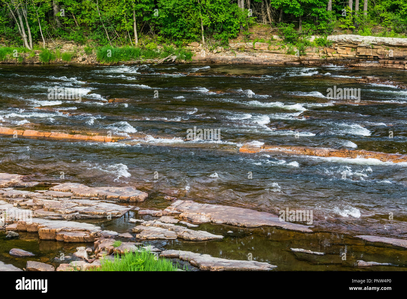 The Ausable River in the summer time flowing over rocks to form rapids ...