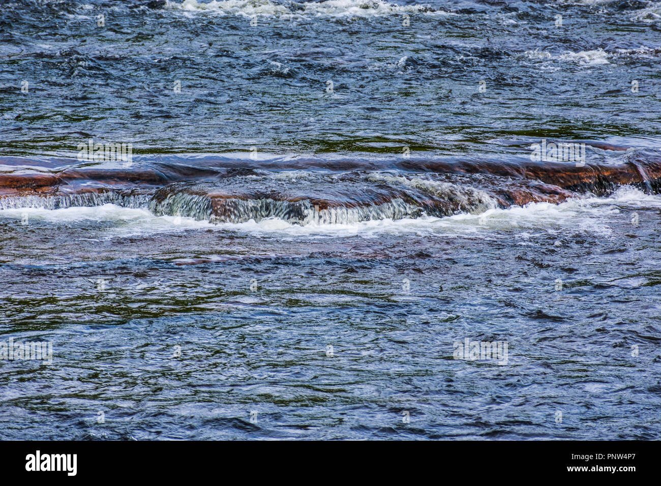 A river flowing over rocks to form little waterfalls Stock Photo - Alamy