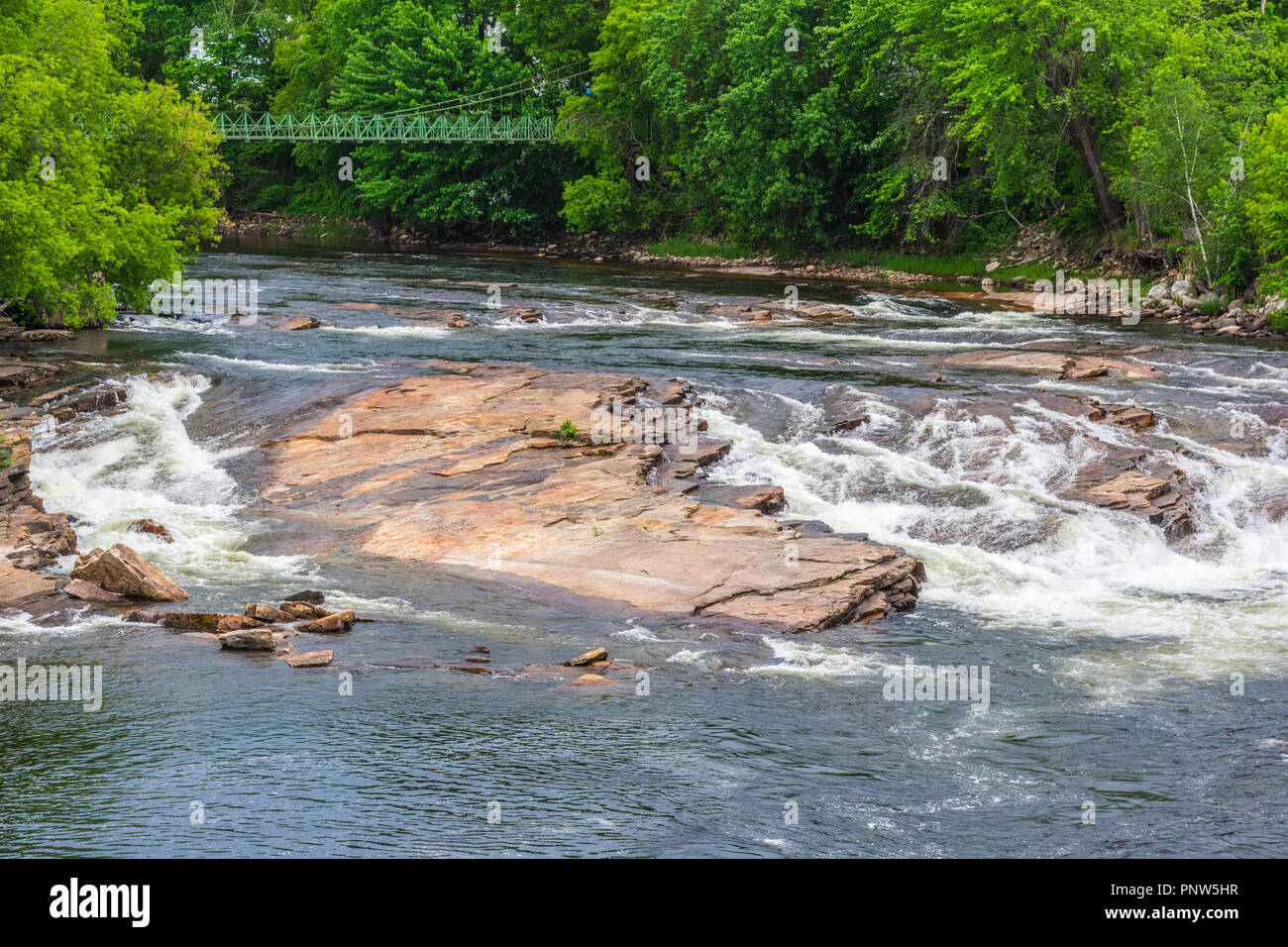 The Ausable River in the summer time flowing over rocks to form rapids ...