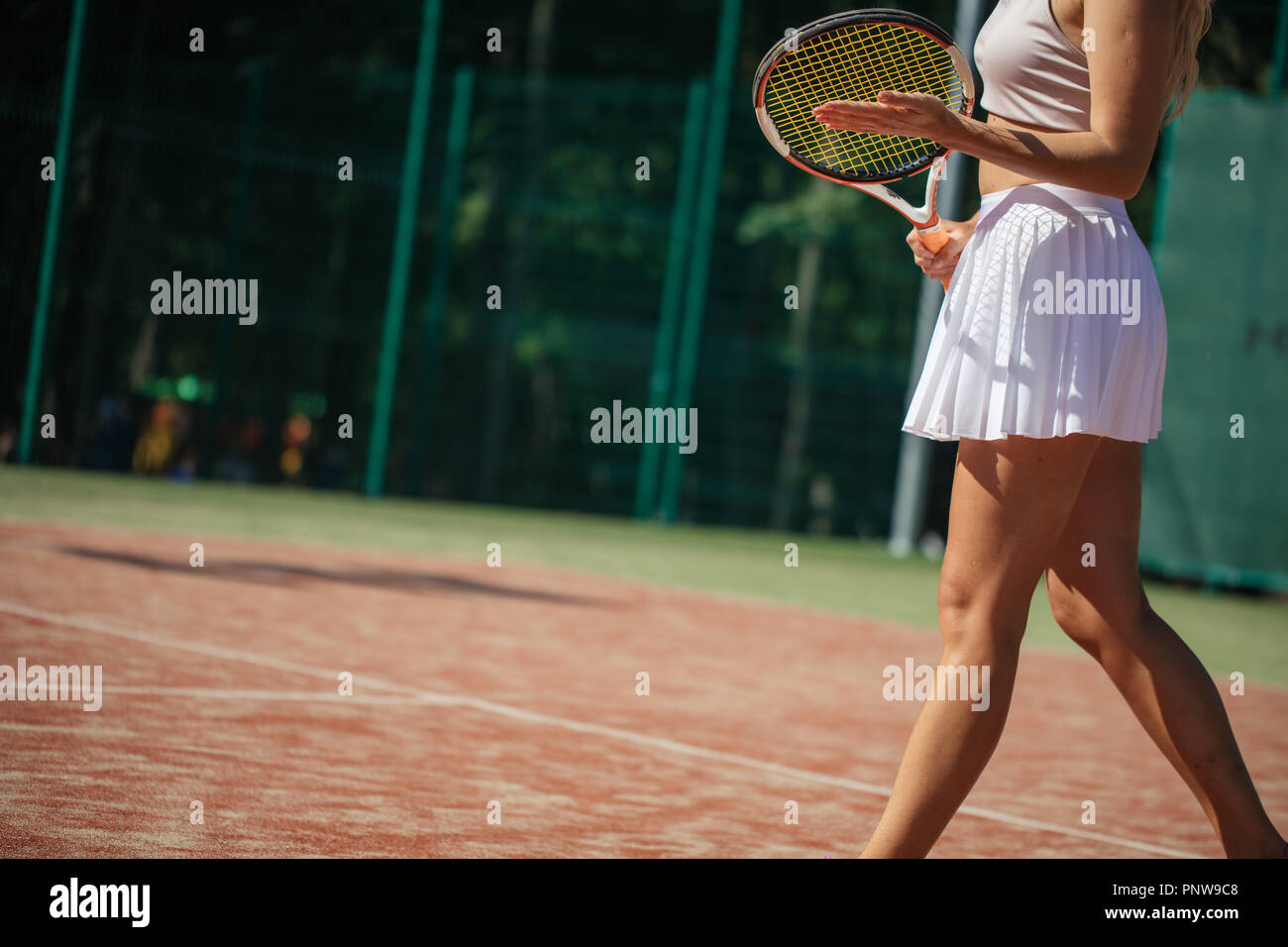 Portrait of female legs with tennis racket on court. close up image ...