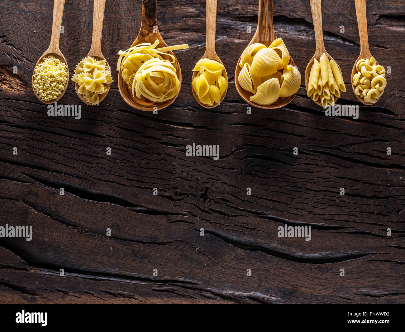 Different pasta types in wooden spoons on the table. Top view Stock ...