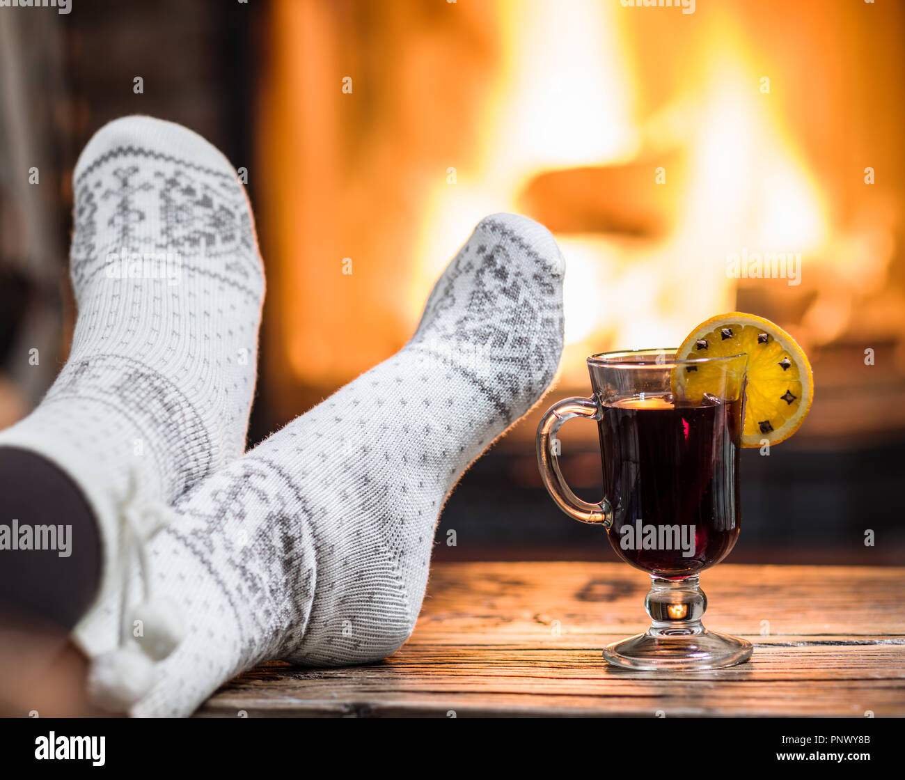 Warming and relaxing near fireplace. Woman feet near the cup of hot ...