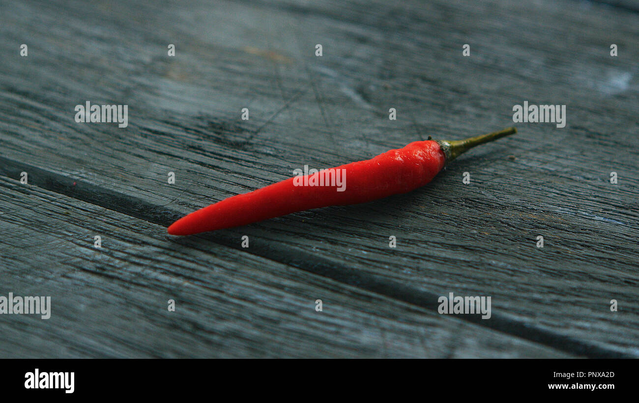 Single red chili pepper on table Stock Photo - Alamy