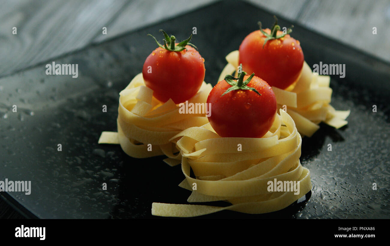 Spaghetti rolled in balls with tomatoes Stock Photo - Alamy