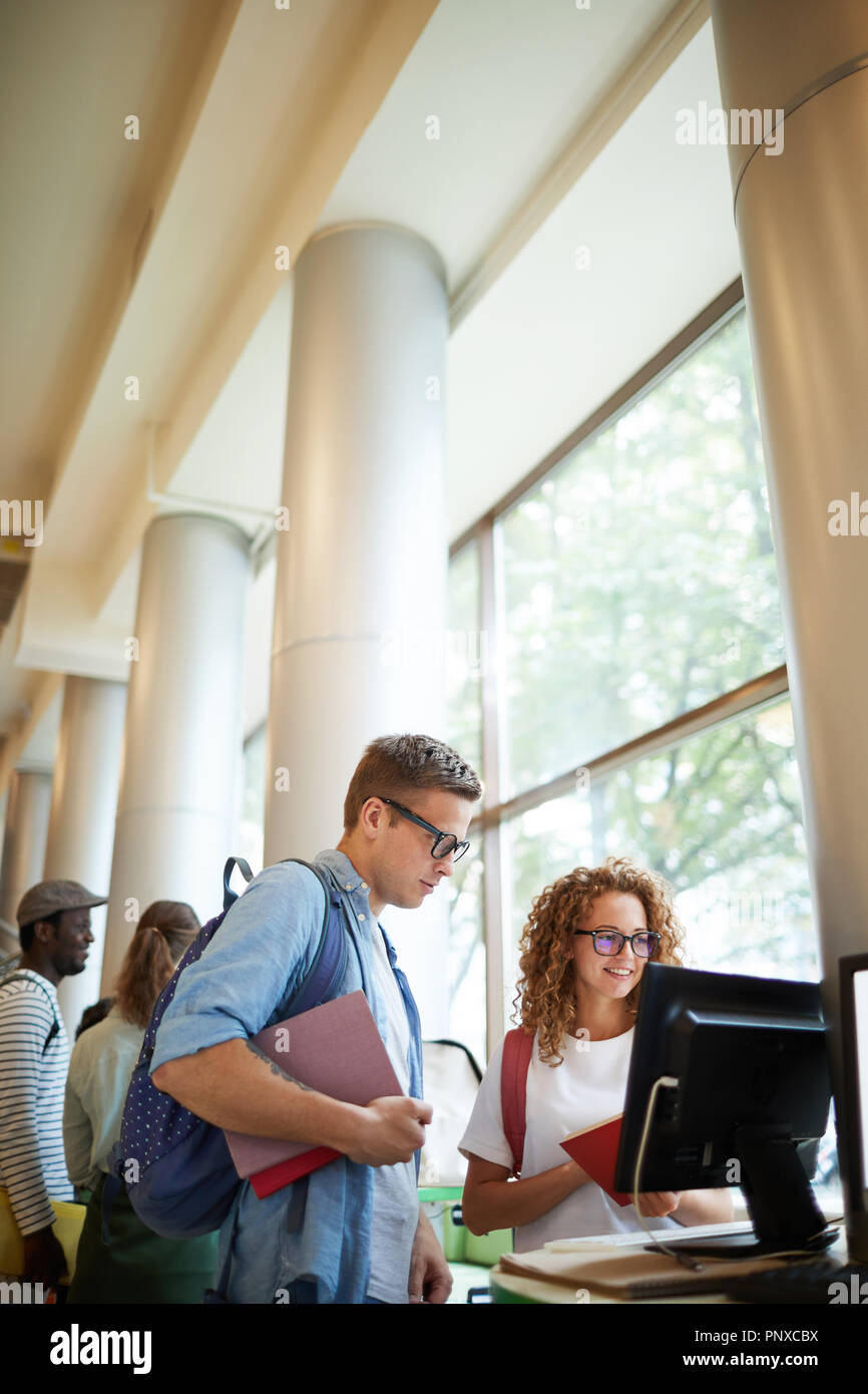 Contemporary students looking at computer screen while searching for ...