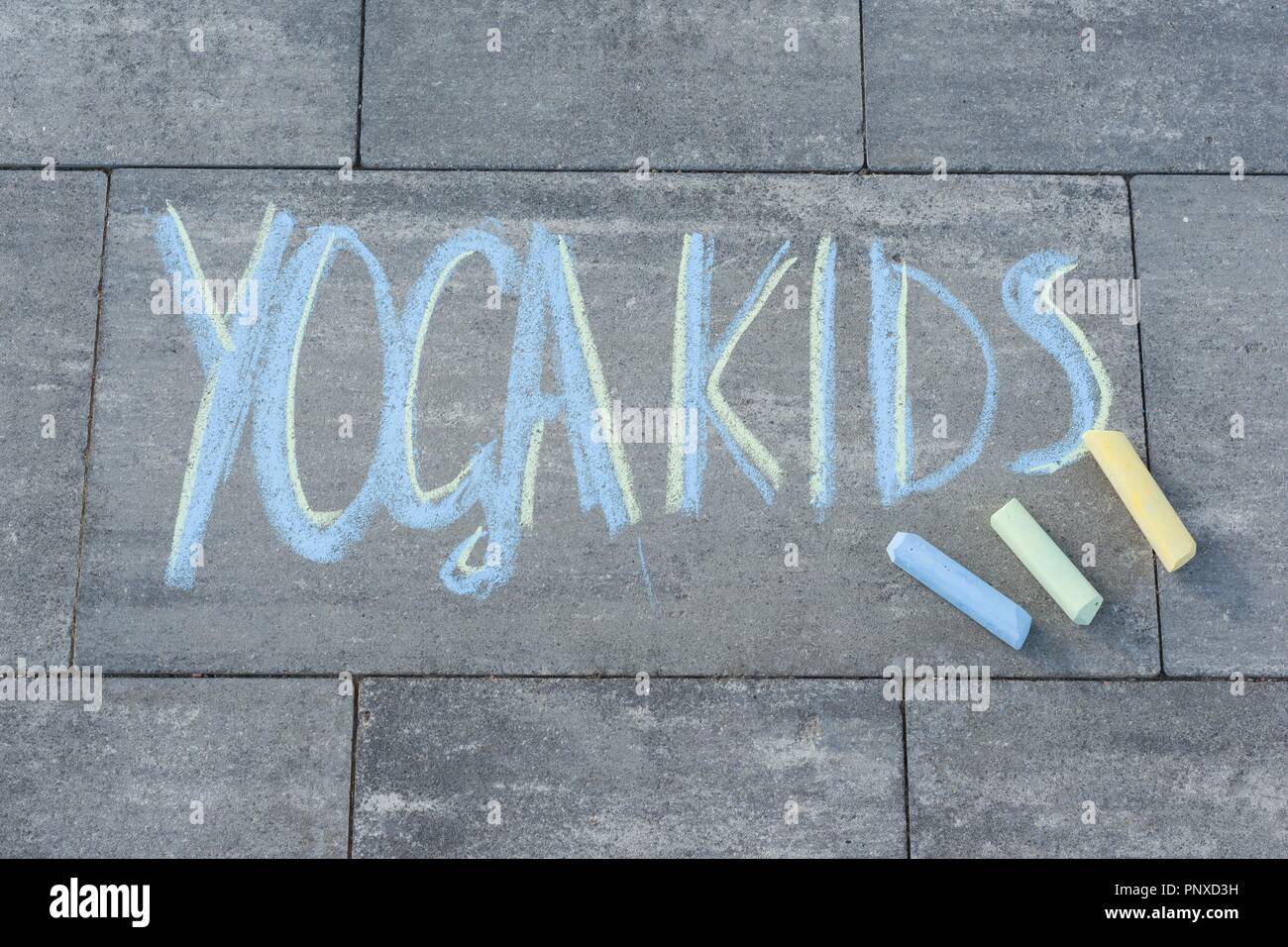 Yoga kids text written by children on the paving slab with colored ...