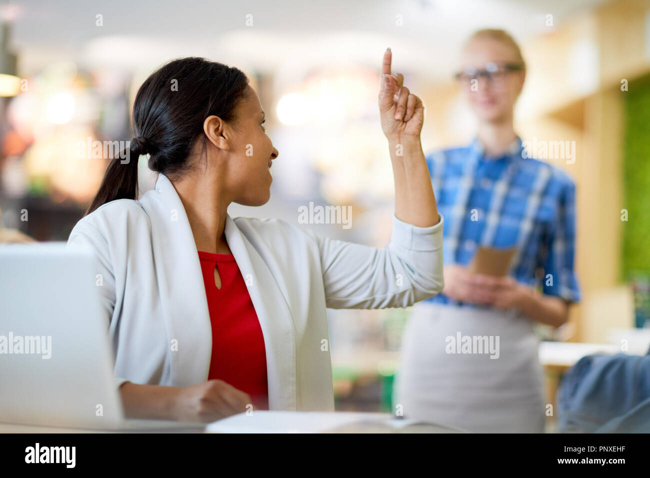 Young businesswoman turning back while looking at waitress and snapping ...