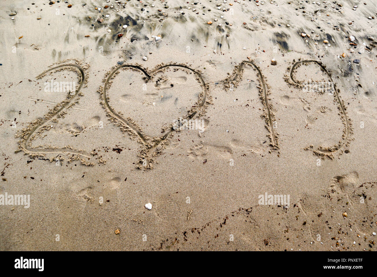 2019 written on the sea sand with heart shaped number 0. Natural sand ...