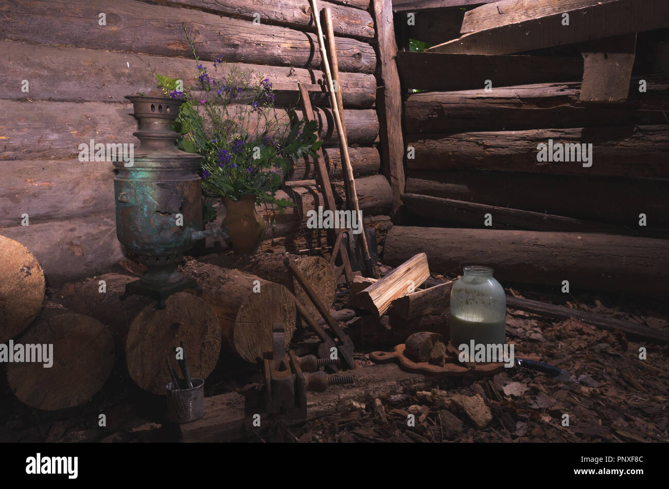Firewood in the corner of the barn. Tools for wood. A dark wooden barn ...