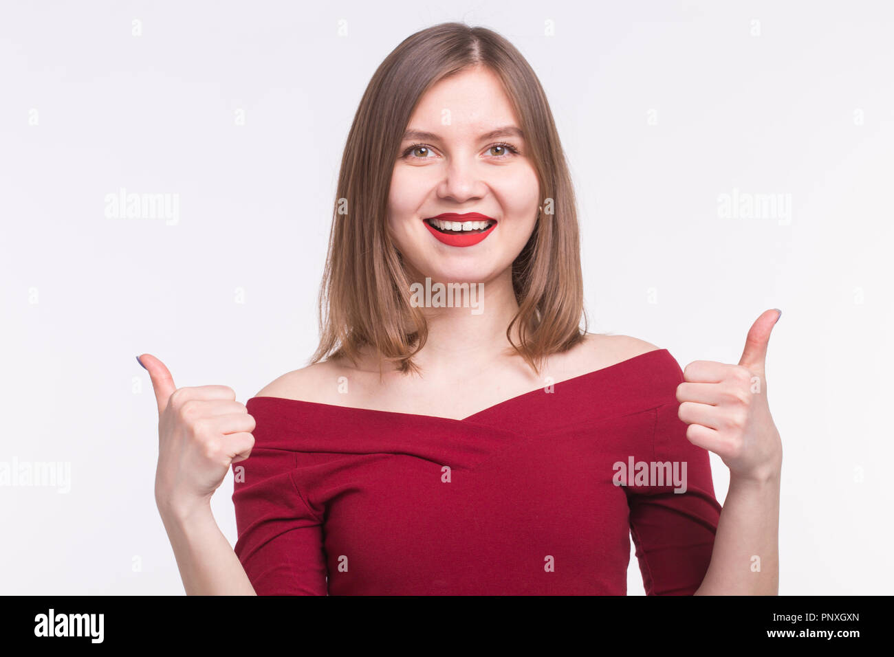 Portrait of happy girl with red lips and thumbs up on white background ...