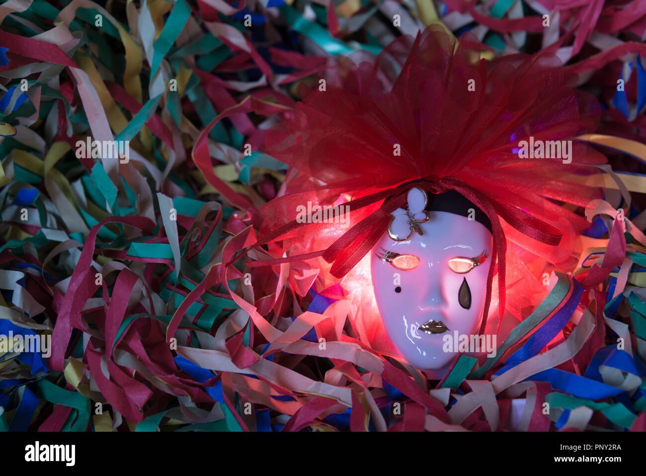 Close-up of Pierrot carnival mask on a background of colored streamers ...