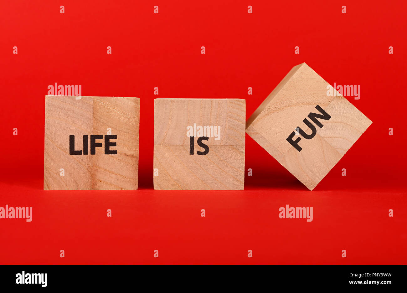 Close up three wooden cube signs with LIFE IS FUN words over red ...