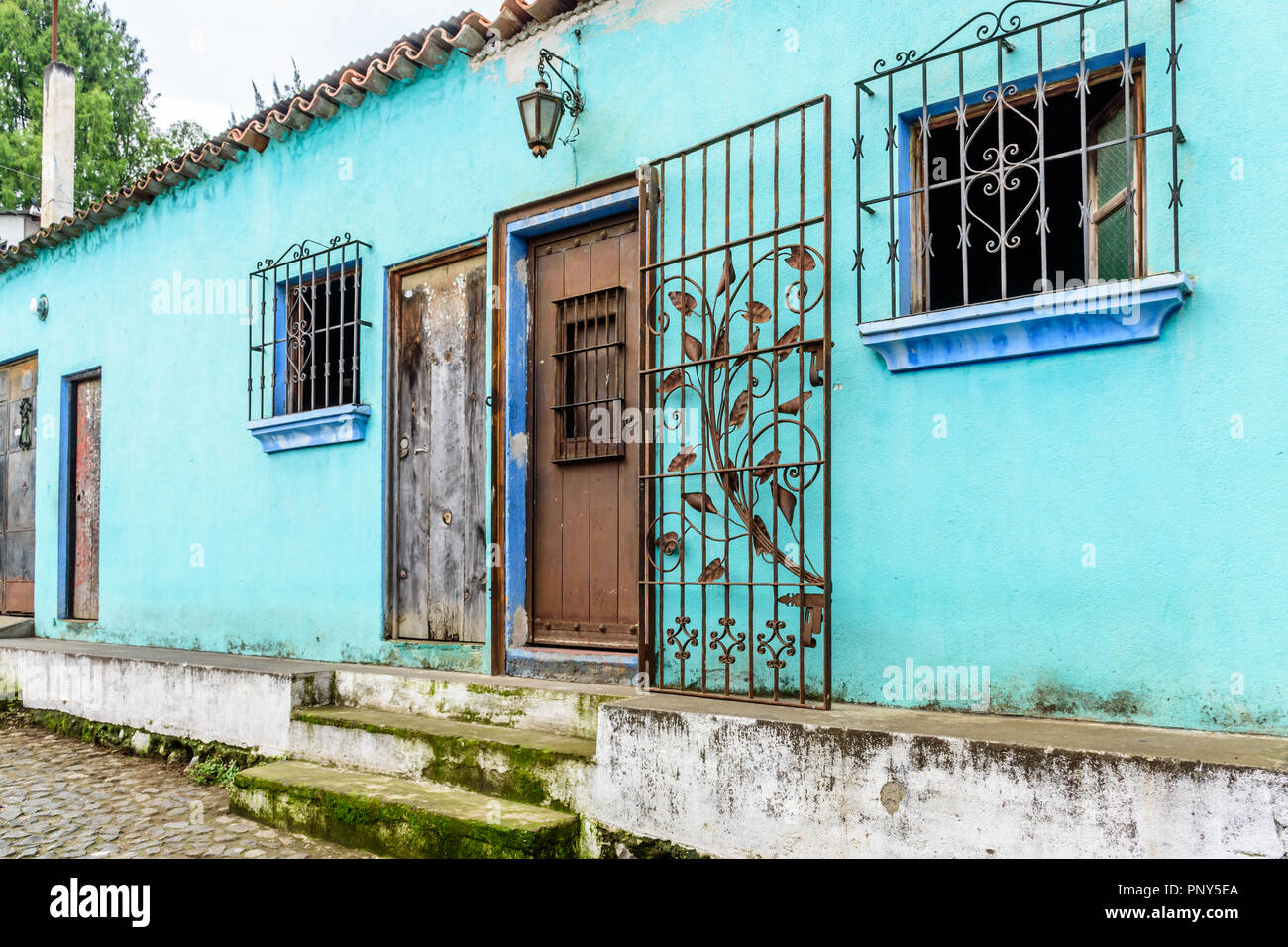 Turquoise painted house exterior with decorated wrought iron bars on ...