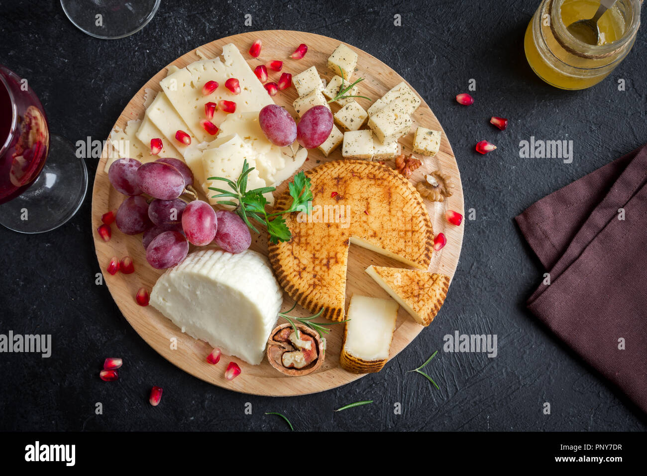 Cheese platter with assorted cheeses, grapes, nuts on black background ...