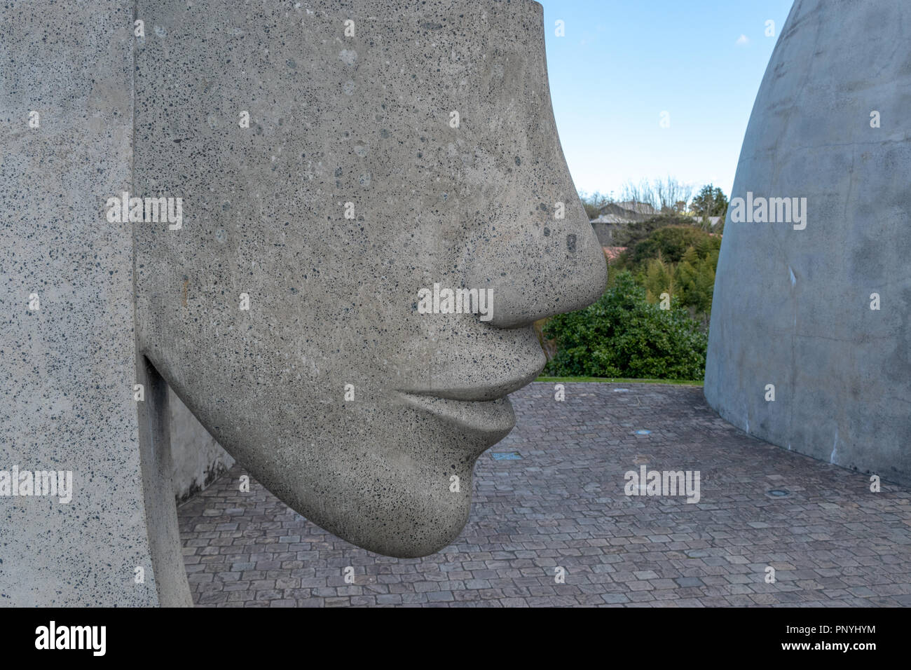 Large side profile sculpture of a woman's face outdoor against a blue ...