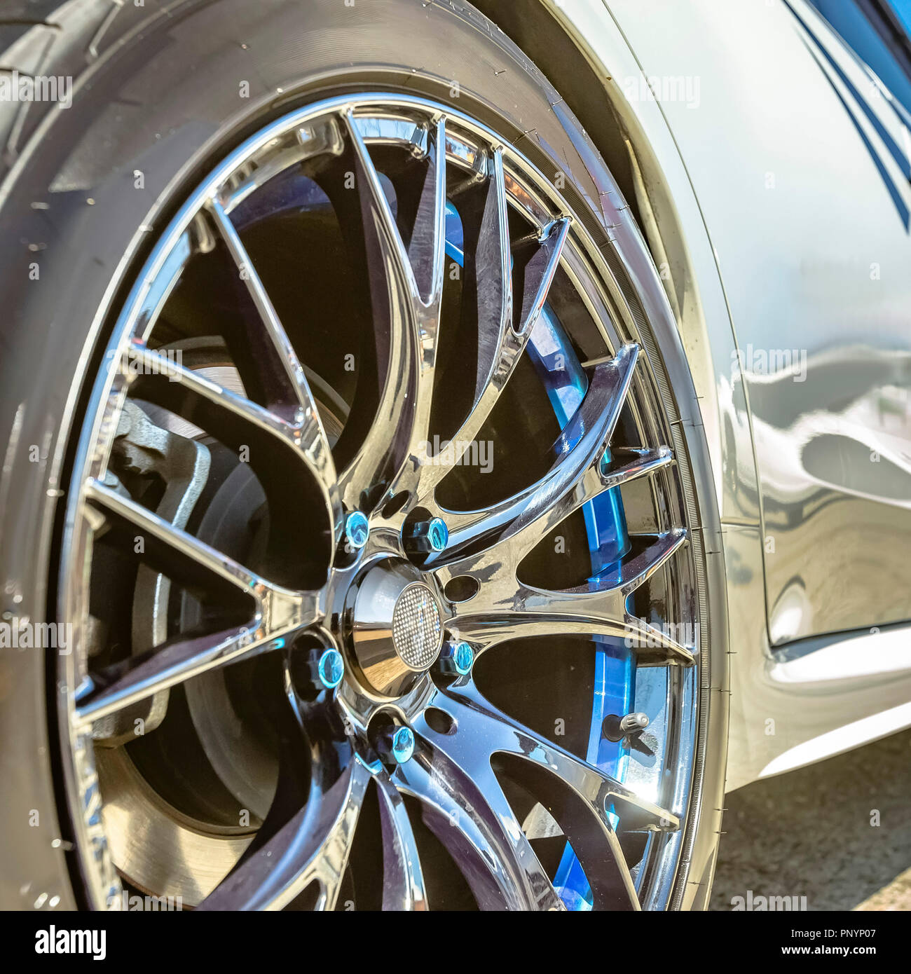 Silver tire rim with blue bolts of a white car Stock Photo - Alamy
