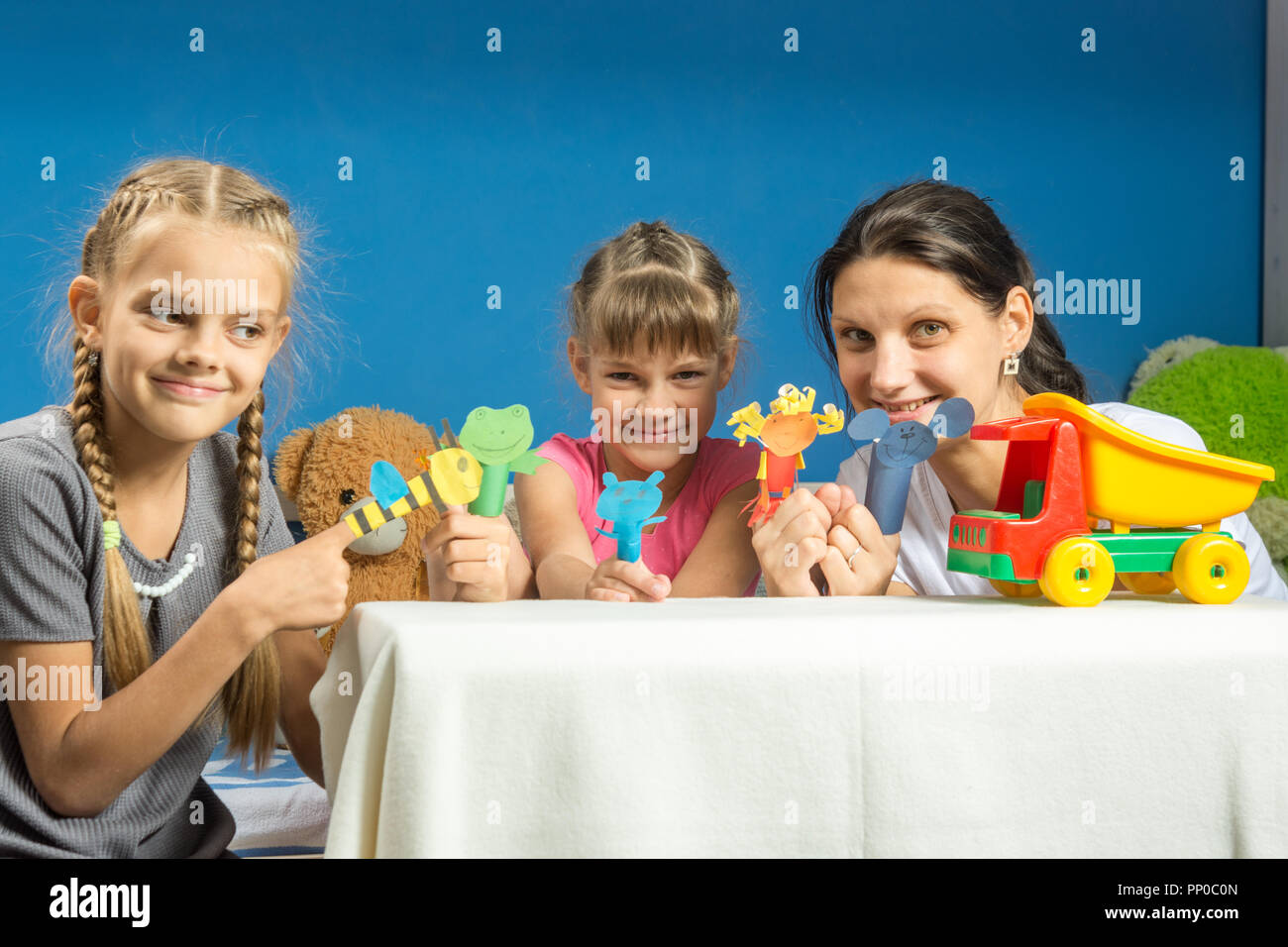 Mom with two daughters playing in a makeshift finger puppet theater ...