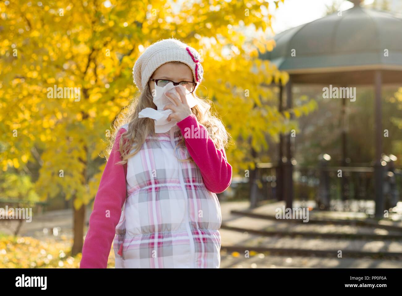 Frozen sick girl with a handkerchief, background yellow autumn trees ...