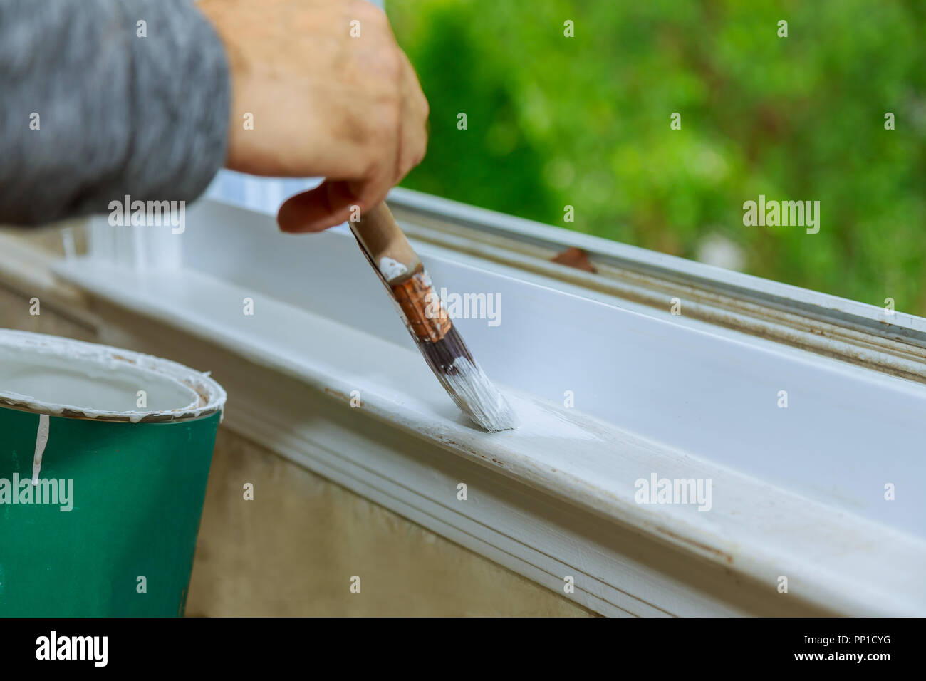 painting a window frame trim in her home with white color Stock Photo ...