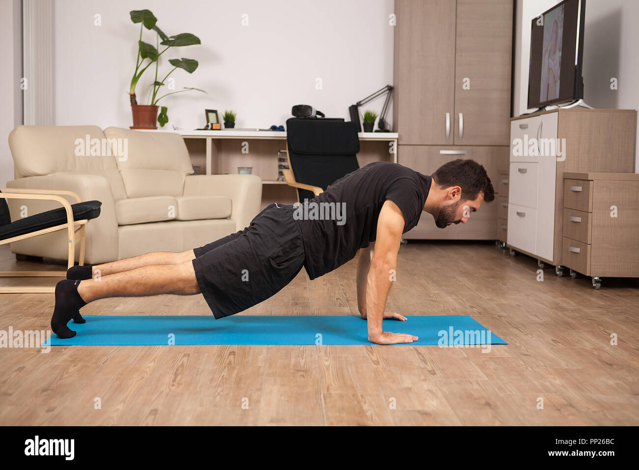 bearded man doing push ups on the floor of his house. Practice makes it ...