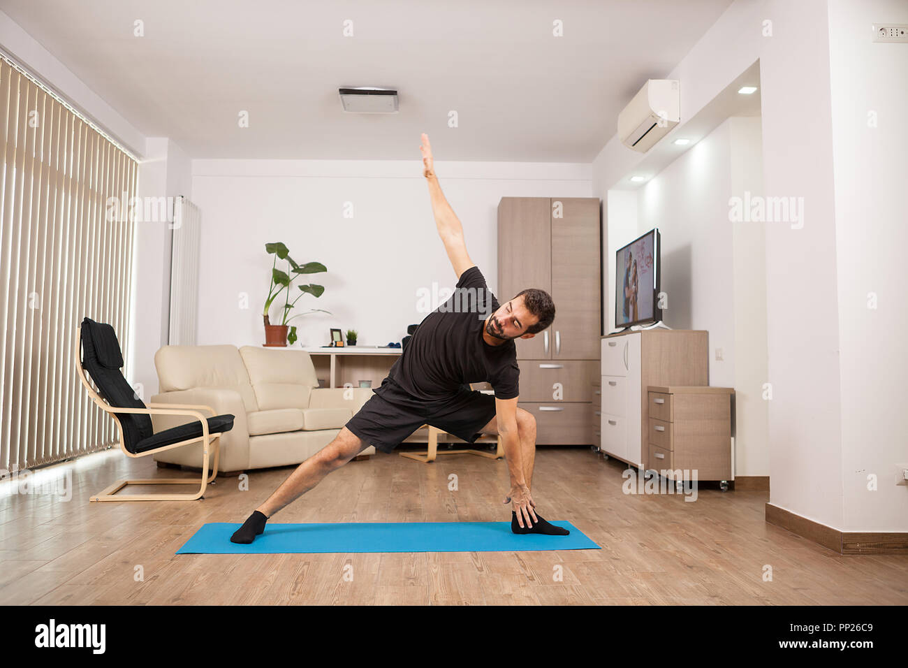 Attractive man trying extended side Yoga poses on his house floor ...