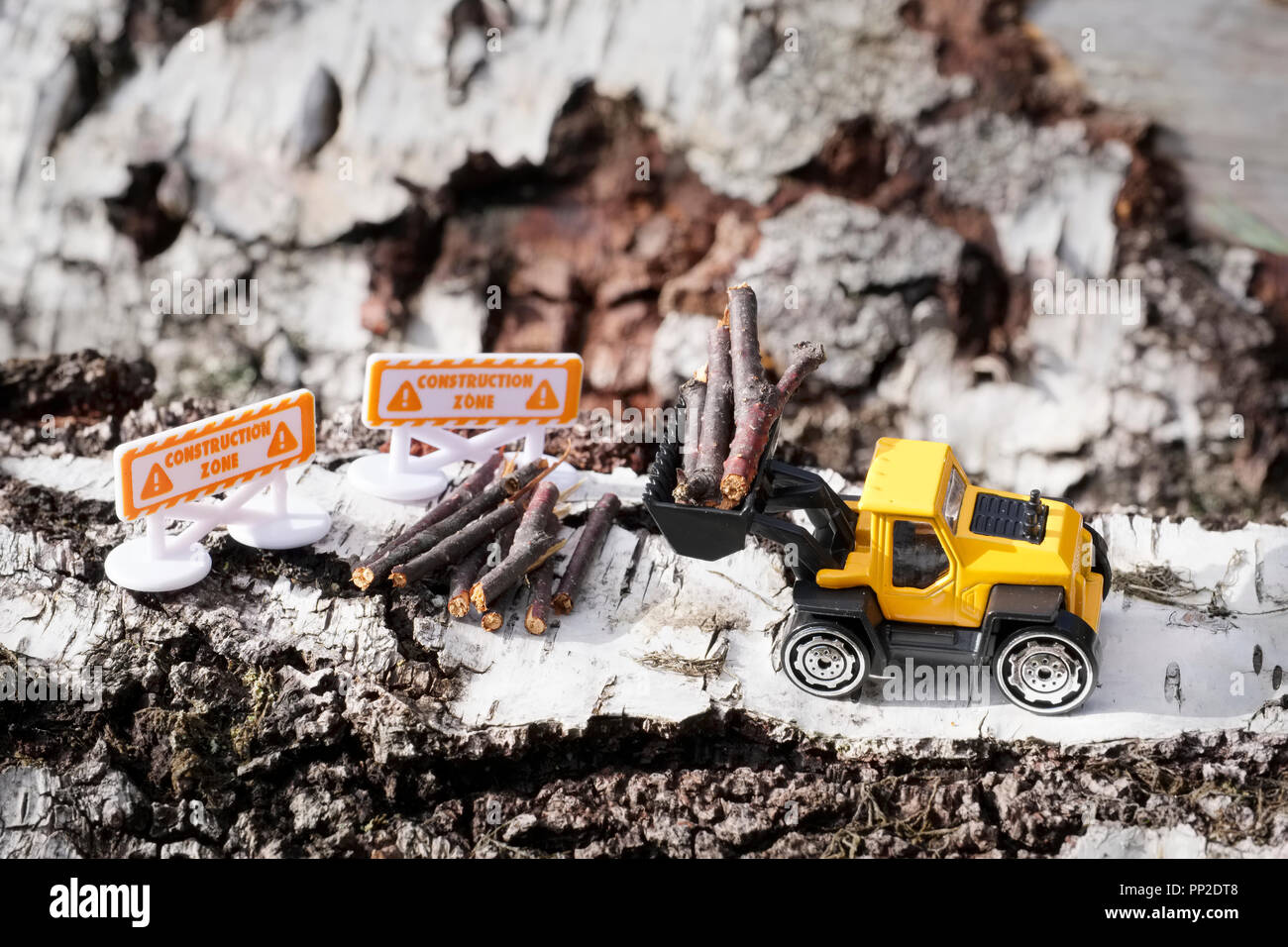 Yellow toy digger with chopped wood logs and construction signs ...