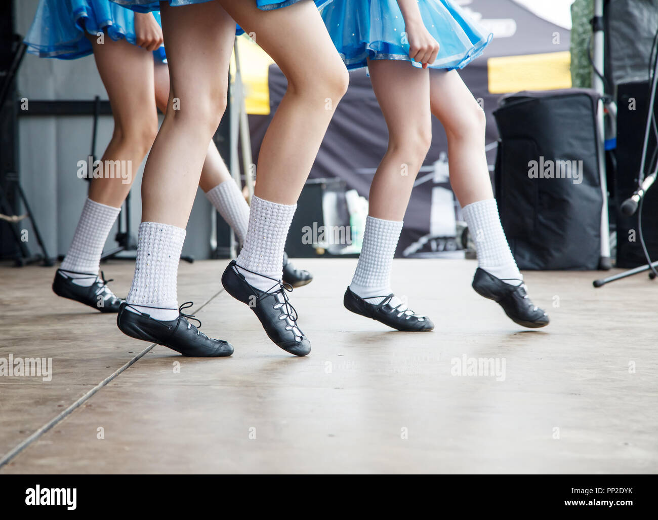 female legs of three irish dancers in blue dresses on the stage closeup ...