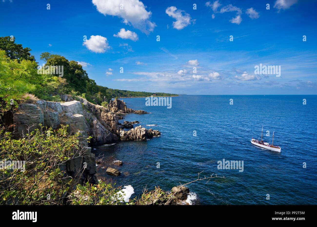 Ship with tourists admiring sheer cliffs of the northern coast of ...