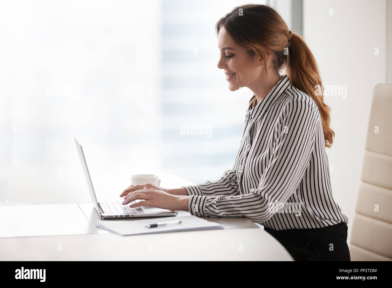 Happy businesswoman texting at laptop distracted from work Stock Photo ...