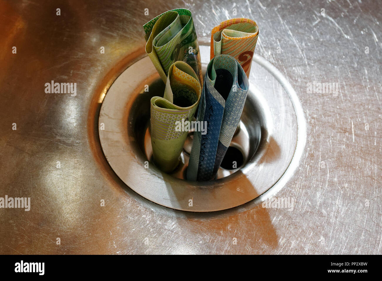 Money down the drain, illustrating waste Stock Photo - Alamy