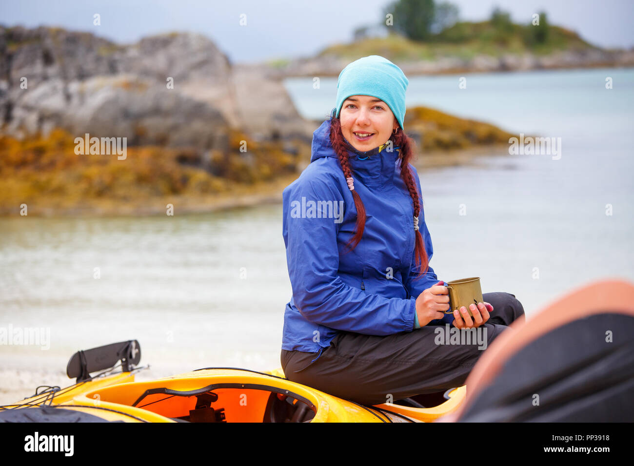 Photo of woman tourist with cup sitting on kayak on river, blurred ...