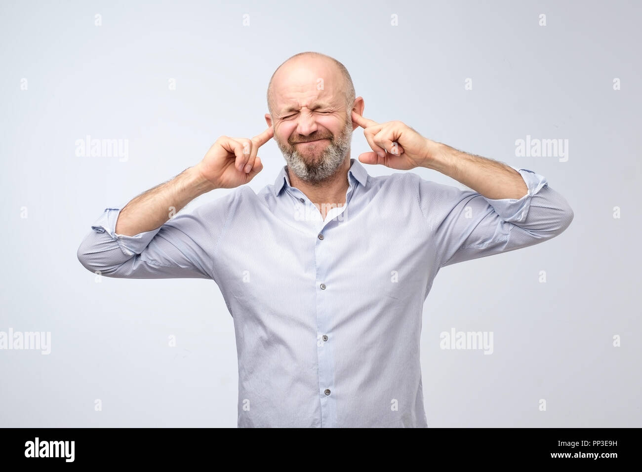 Displeased man plugging ears hi-res stock photography and images - Alamy