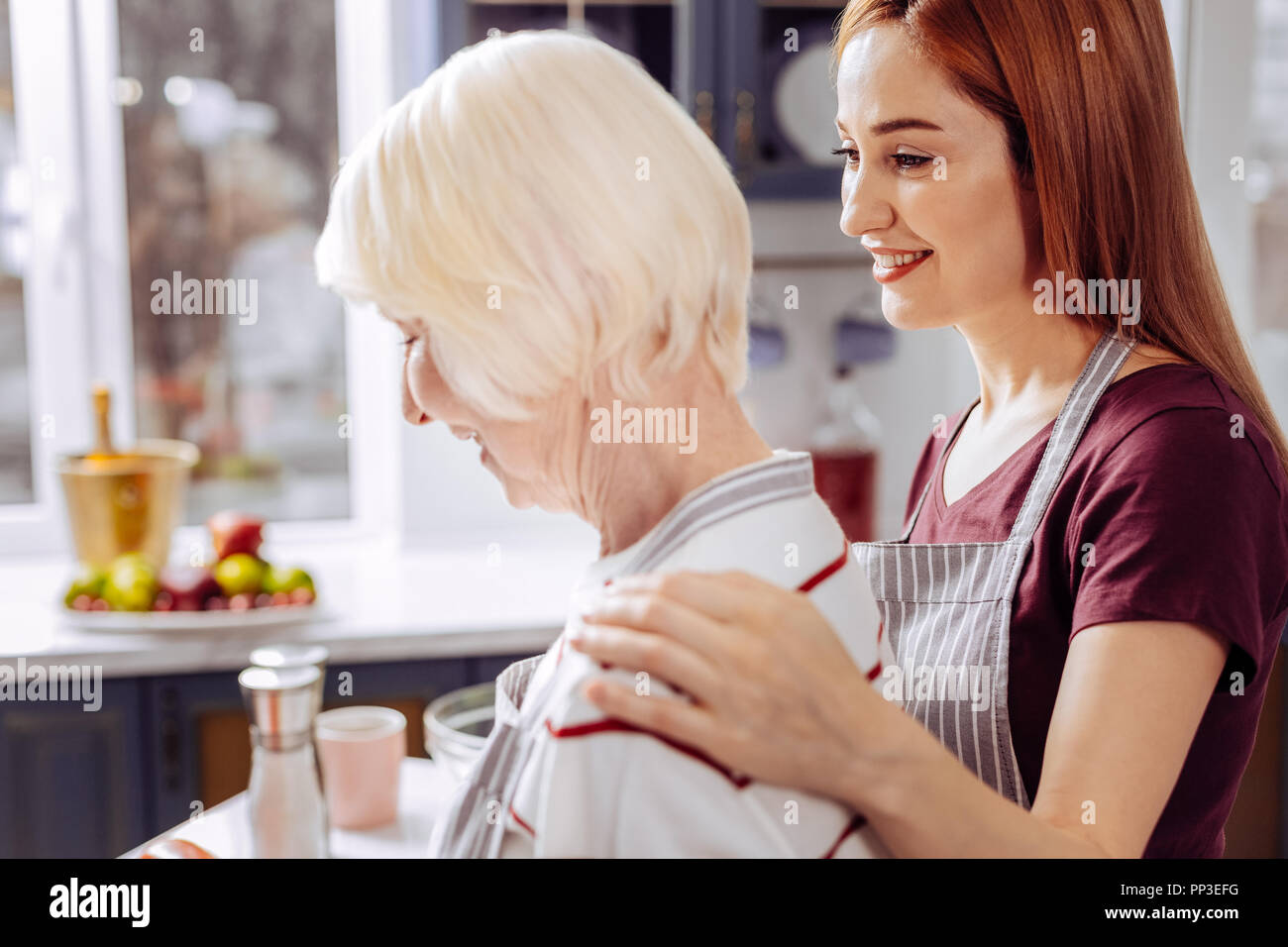 Kind young woman smiling while gently hugging her mother Stock Photo ...