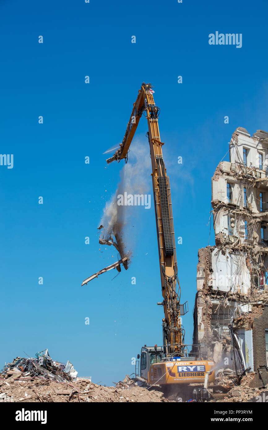 Tall demolition machinery raising a high building to the ground in ...