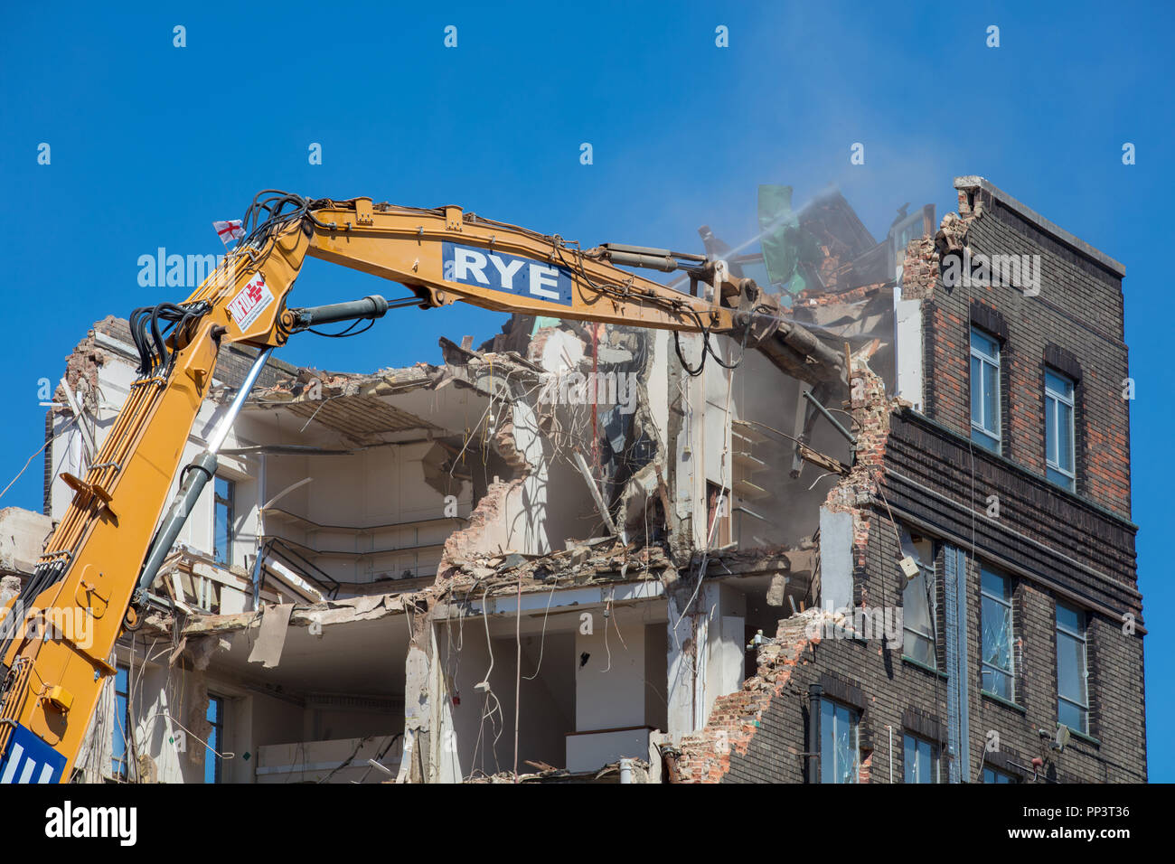 Tall demolition machinery raising a high building to the ground in ...