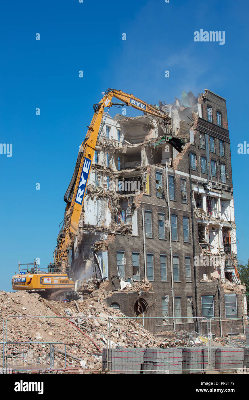 Tall demolition machinery raising a high building to the ground in ...
