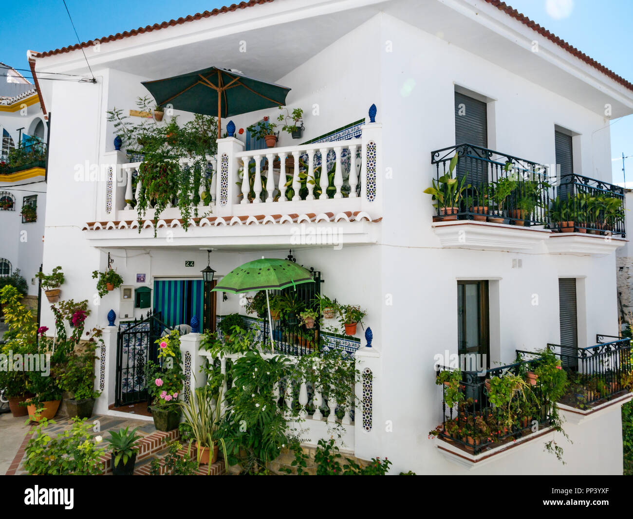Traditional white house with balconies laden with colourful flower pots ...