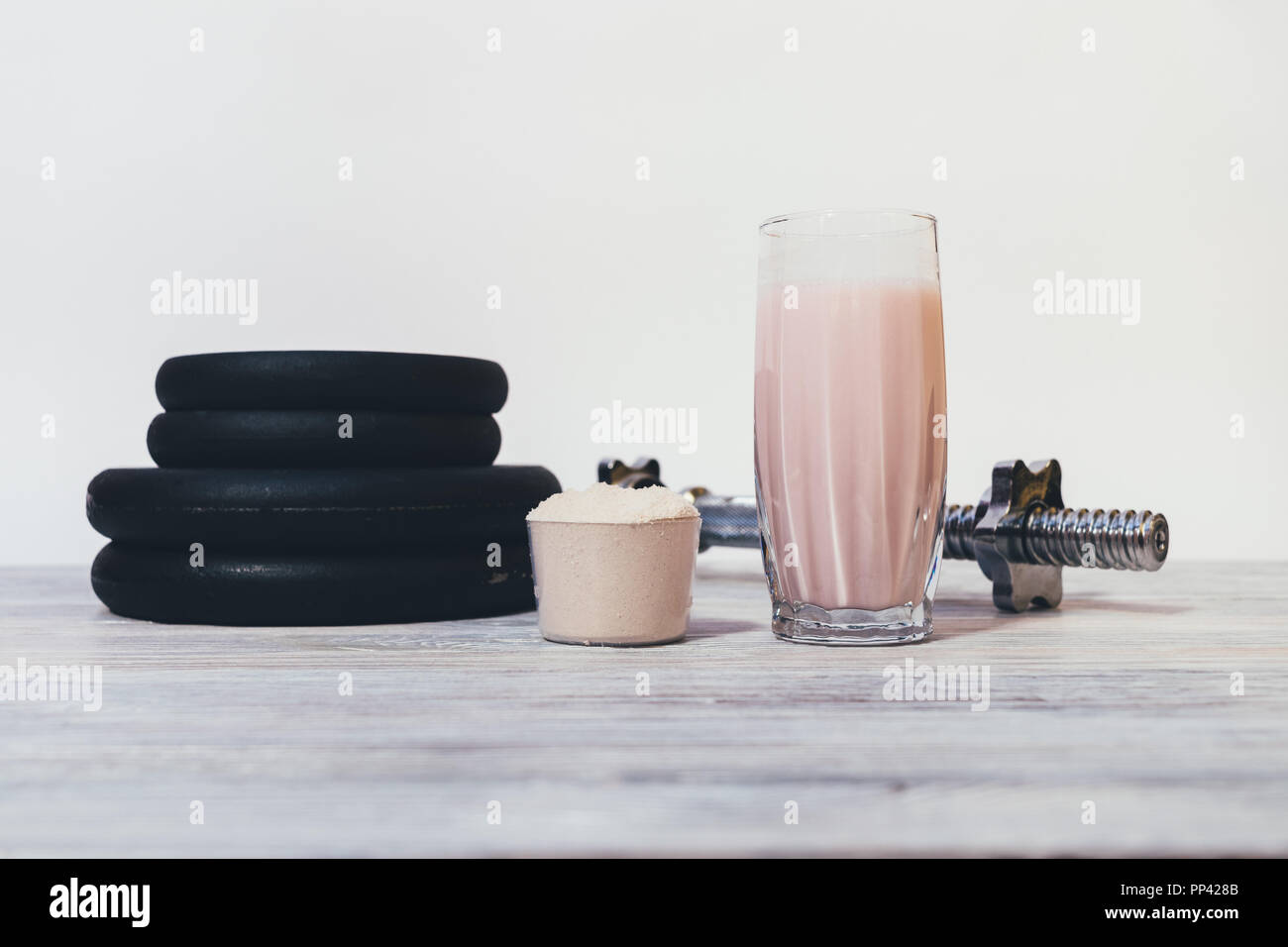 Glass of protein shake next to portion of dry powder in measuring scoop ...