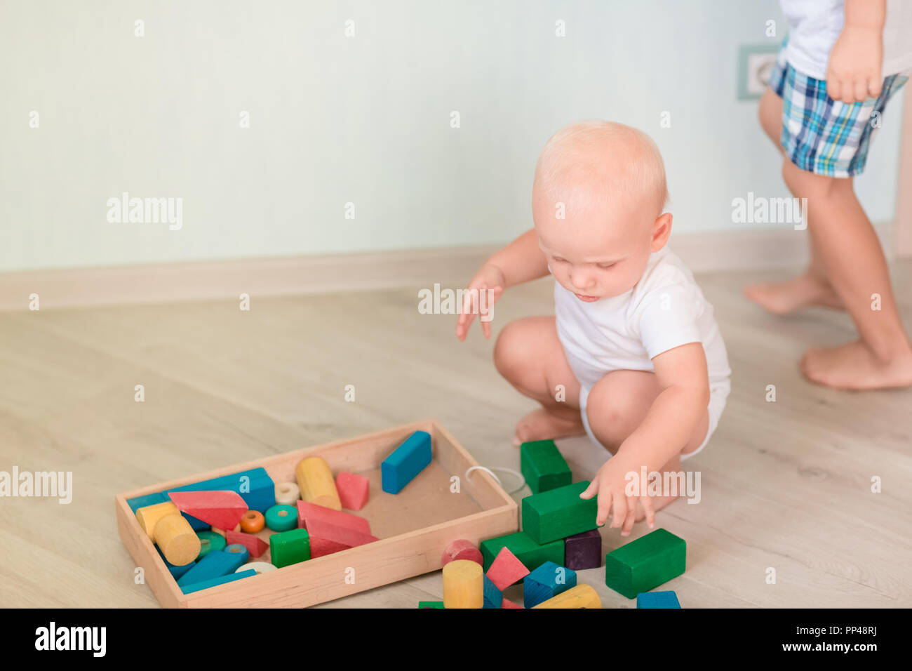 Cute little baby playing with colored wooden blocks in the room. Early ...