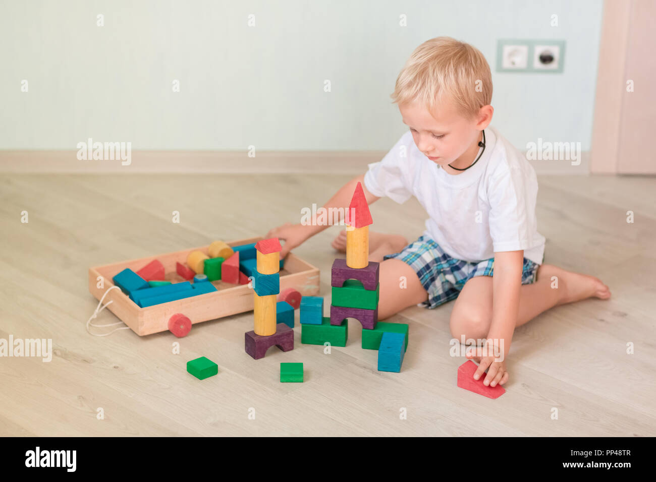Cute little boy playing with colored wooden blocks in the room. Early ...