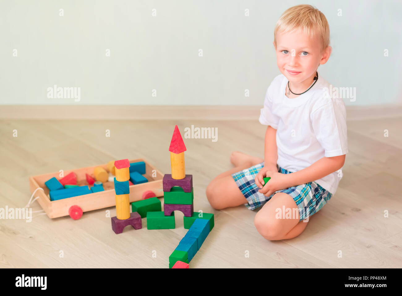 Cute little boy playing with colored wooden blocks in the room. Early ...